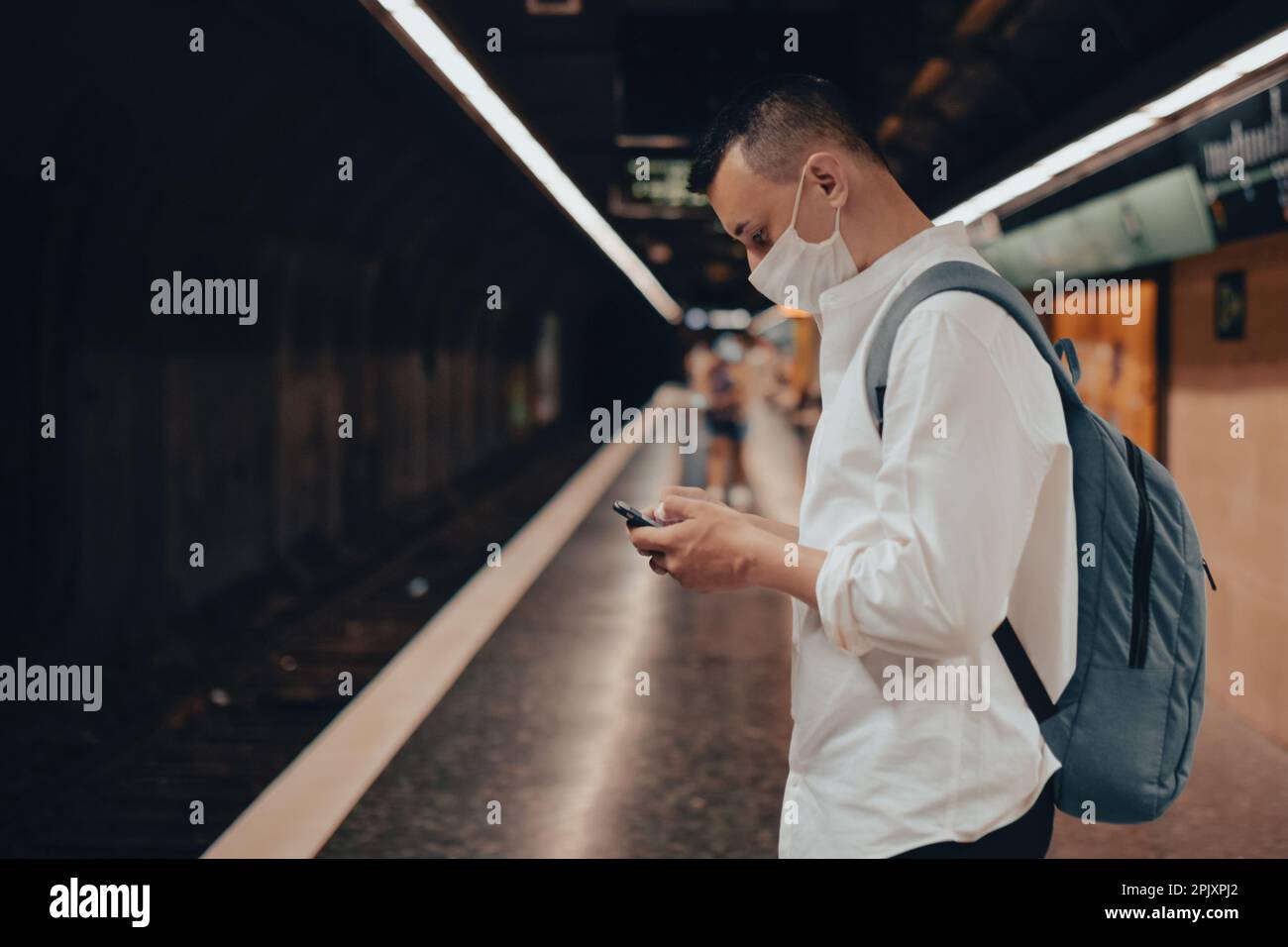 A masked man stands in the subway with a phone in his hands. Actions ...