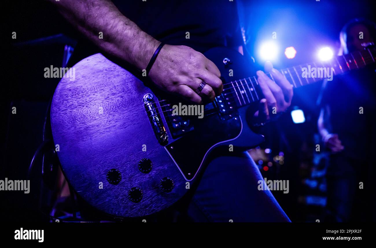 A male guitarist performing on a stage in front of a large crowd of ...