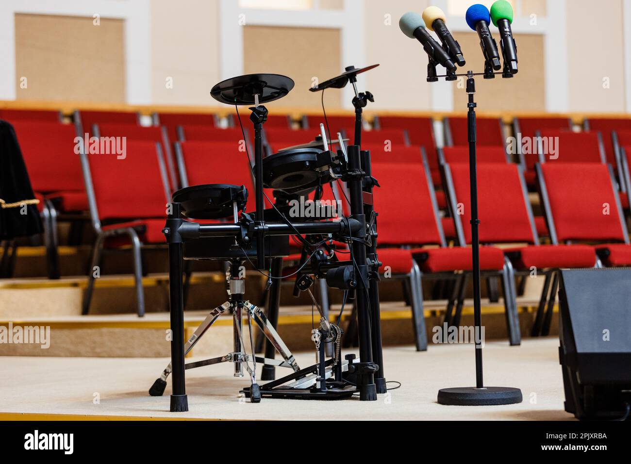 Coloured microphones on stand and electronic drum set on podium, a lot ...