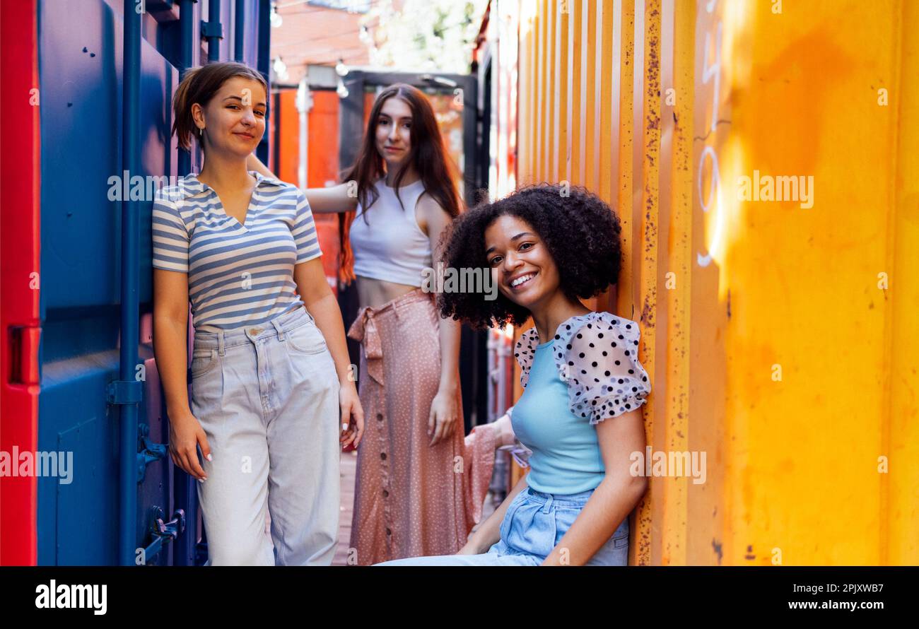 Three cute teenage girls in casual clothes on background of multi ...