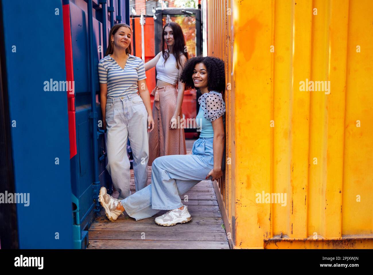 Three cute teenage girls in casual clothes on background of multi ...