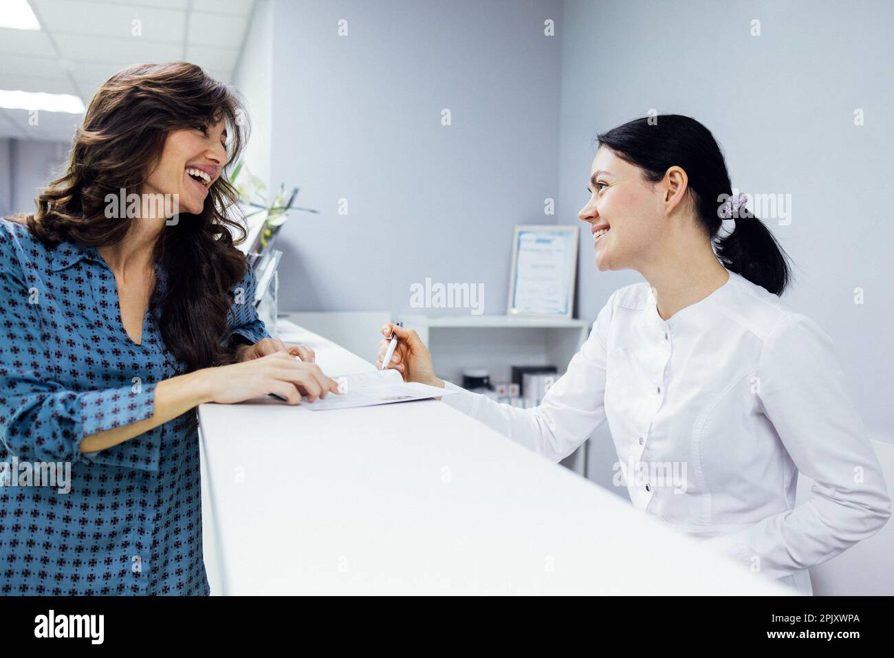 Smiling female client communicates with reception woman in a beauty ...