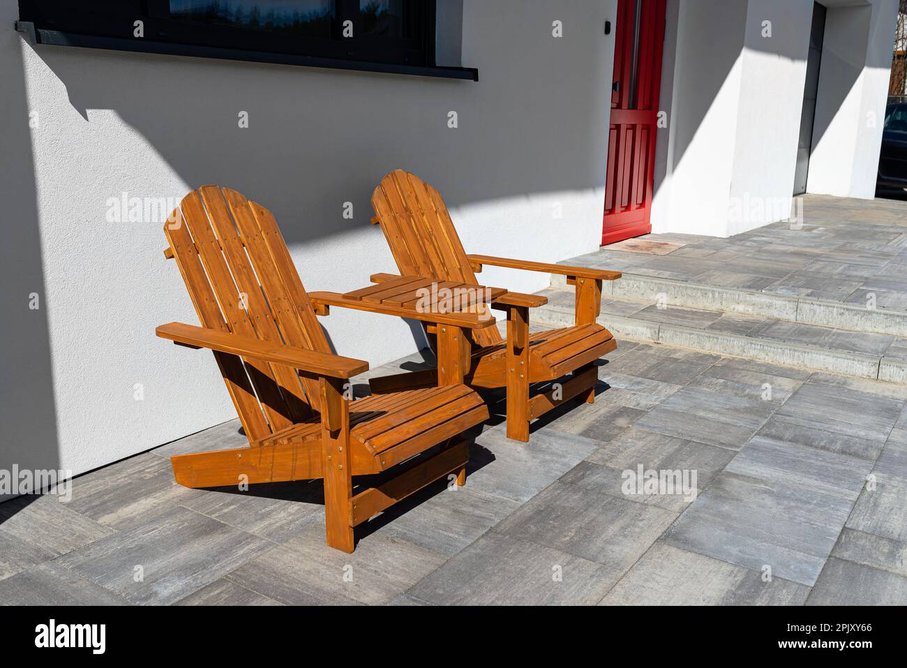 Two wooden chairs connected by a small table standing in front of a ...