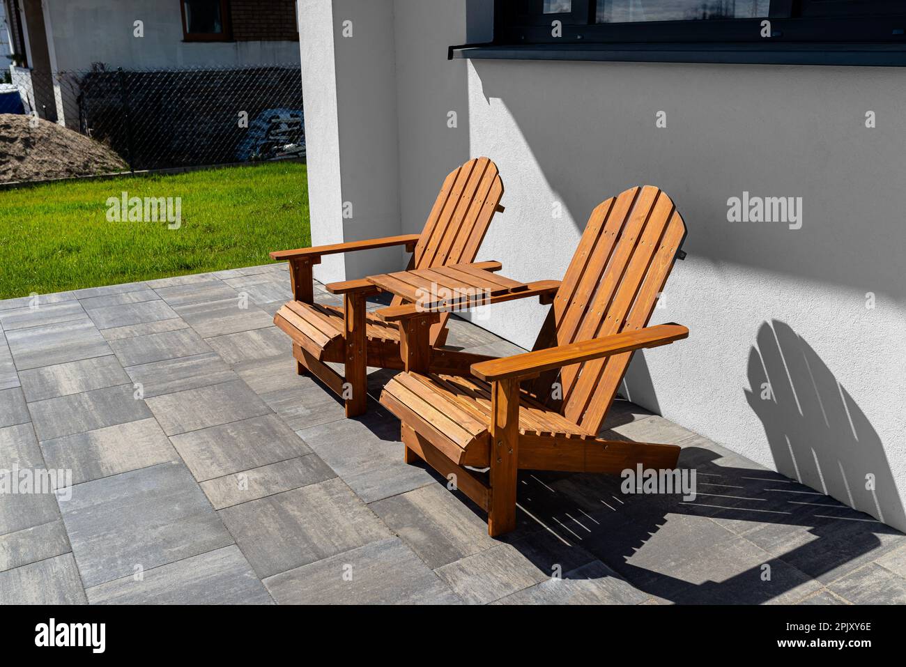 Two wooden chairs connected by a small table standing in front of a ...