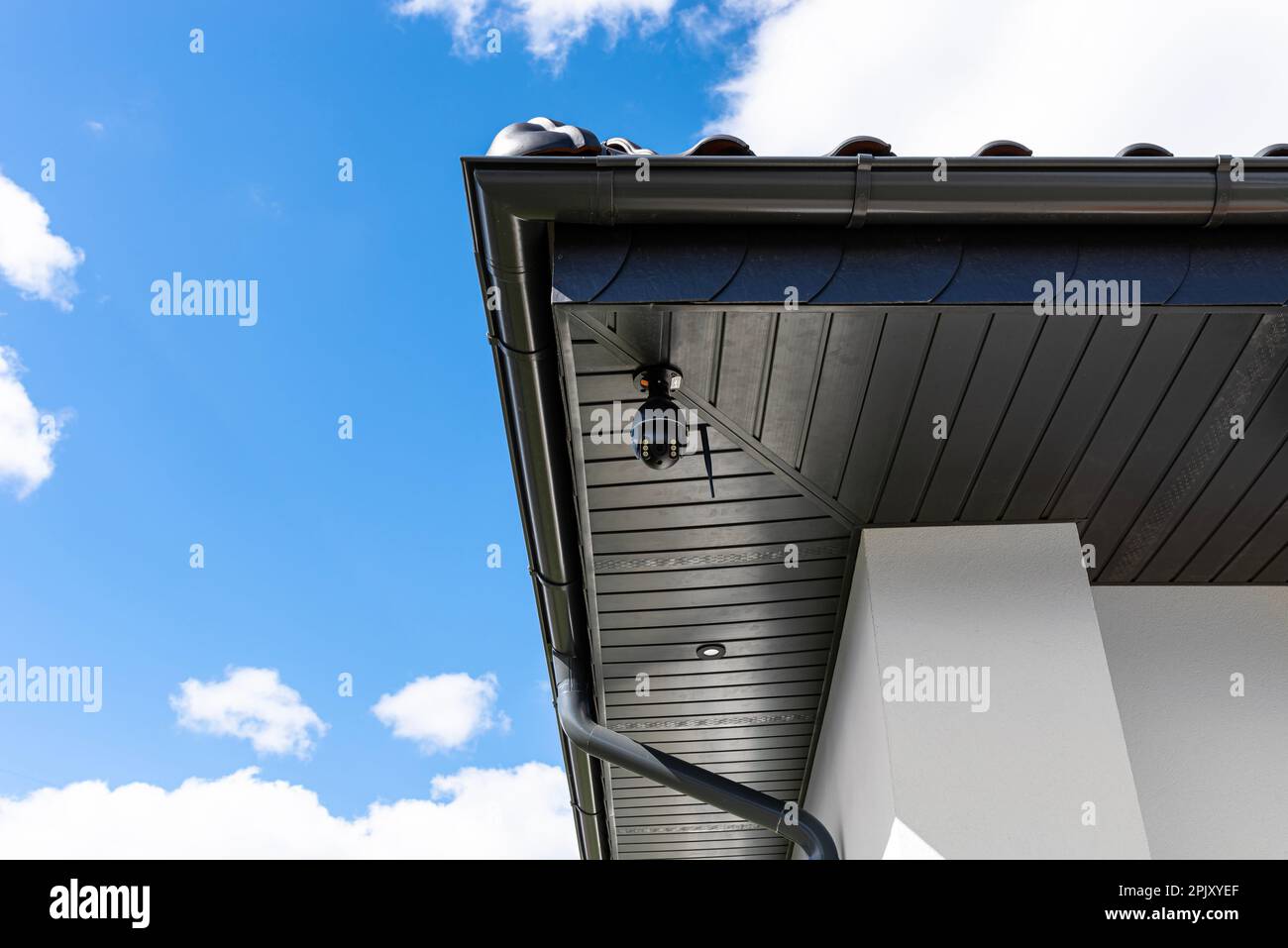 Round wireless camera mounted on the corner of the roof in the soffit ...