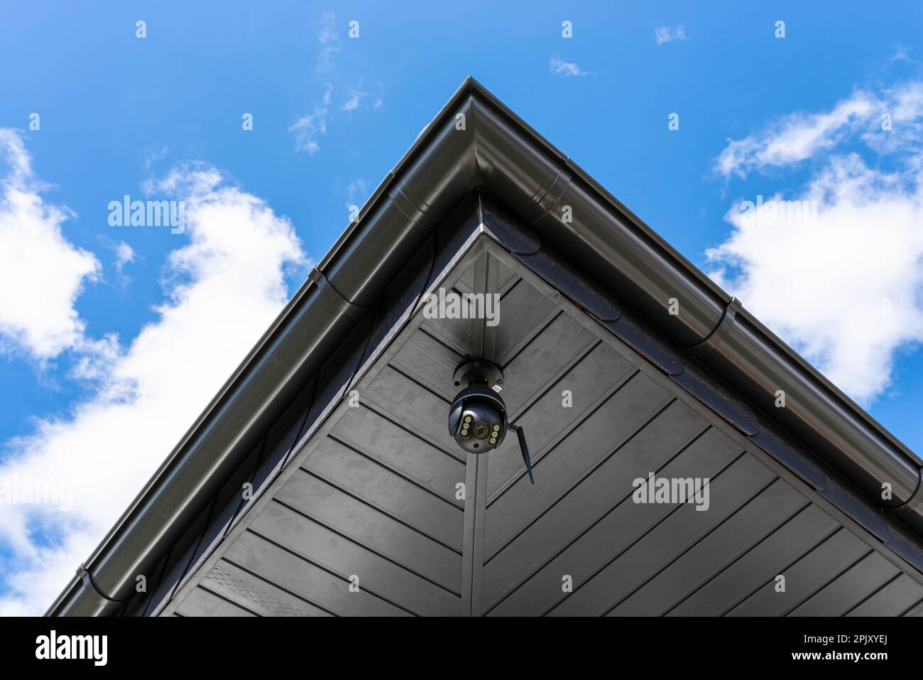 Round wireless camera mounted on the corner of the roof in the soffit ...