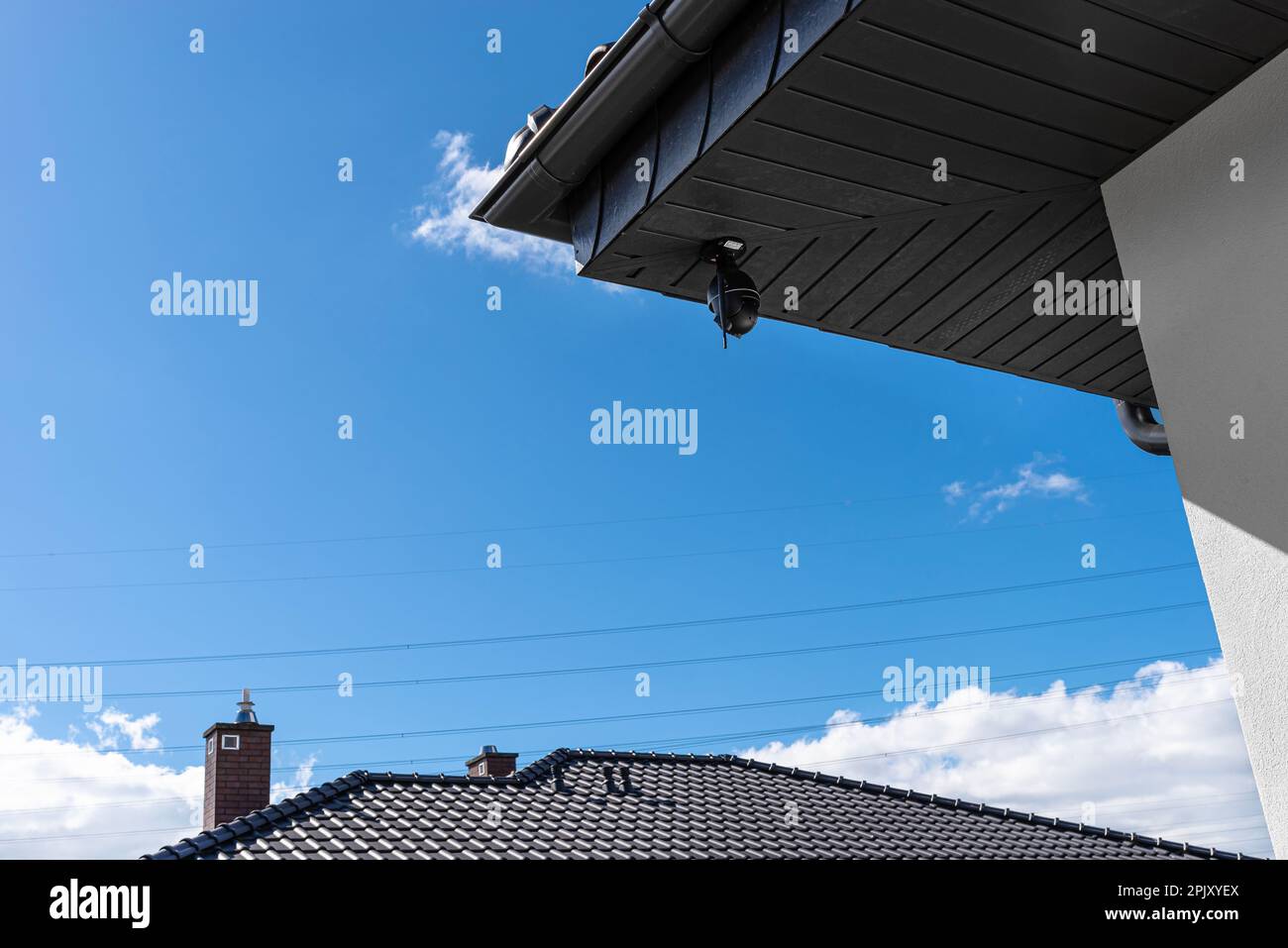 Round wireless camera mounted on the corner of the roof in the soffit ...