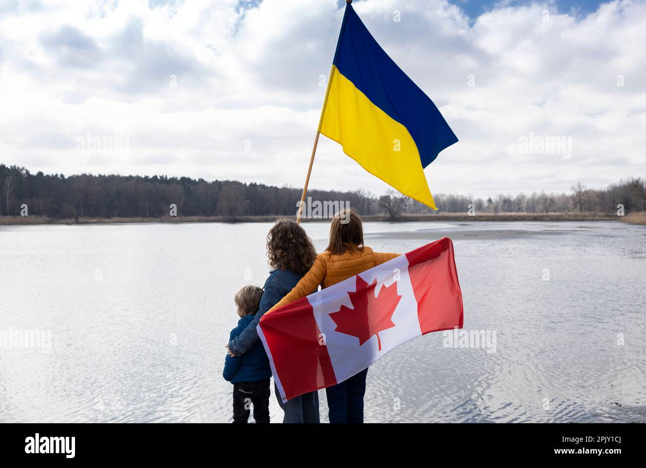 woman with children with Ukrainian and Canadian flags stand together in ...
