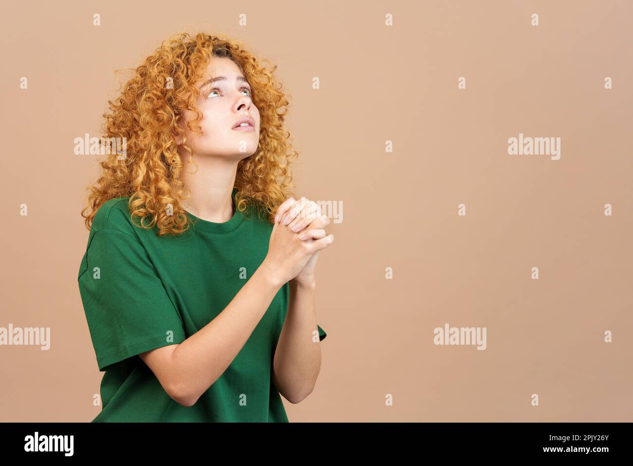 Woman looking up while praying with folded hands Stock Photo - Alamy