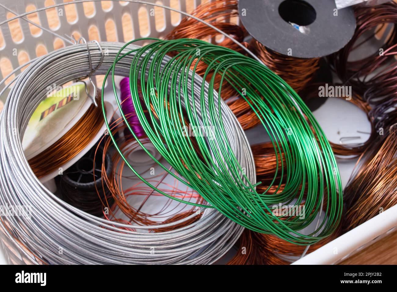 Copper wire coils in a plastic basket close up Stock Photo - Alamy