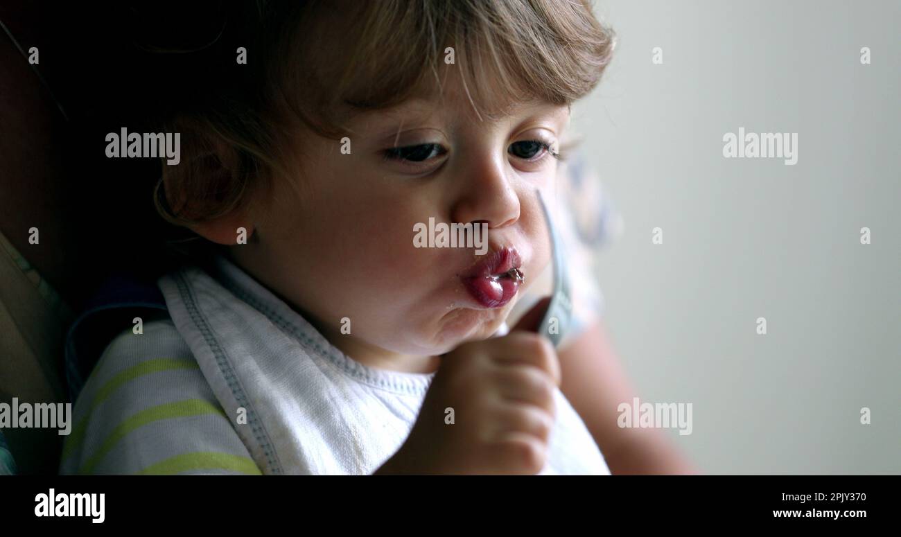 Baby child eating with mother. Candid mom and infant boy eating meal ...