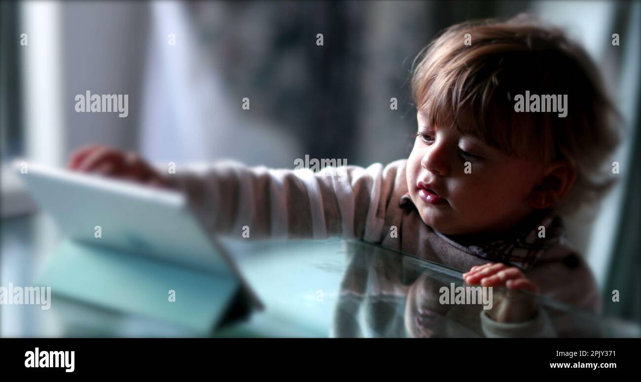 Child watching cartoon on tablet screen. Toddler baby using tech device ...