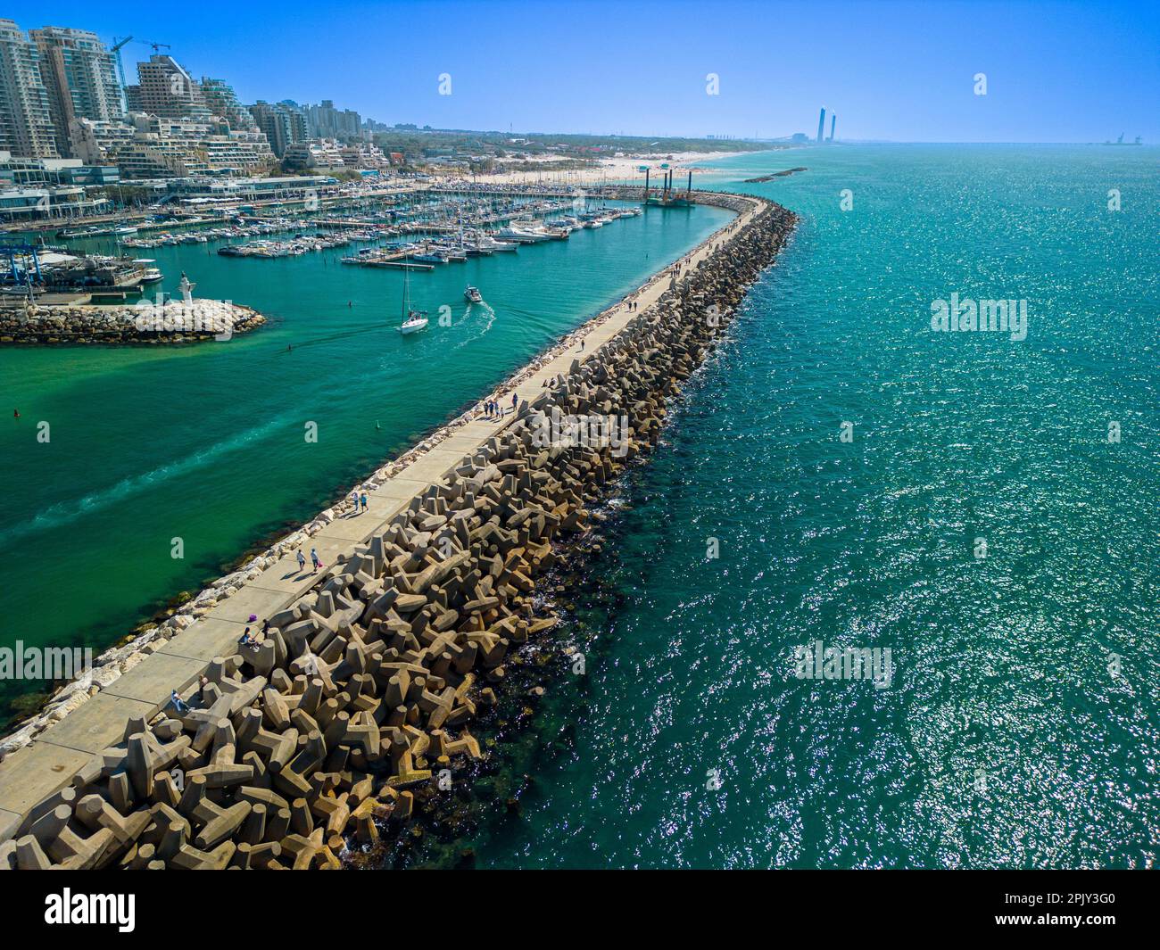 Aerial view of a pier constructed of rocks overlooking a sun-kissed ...