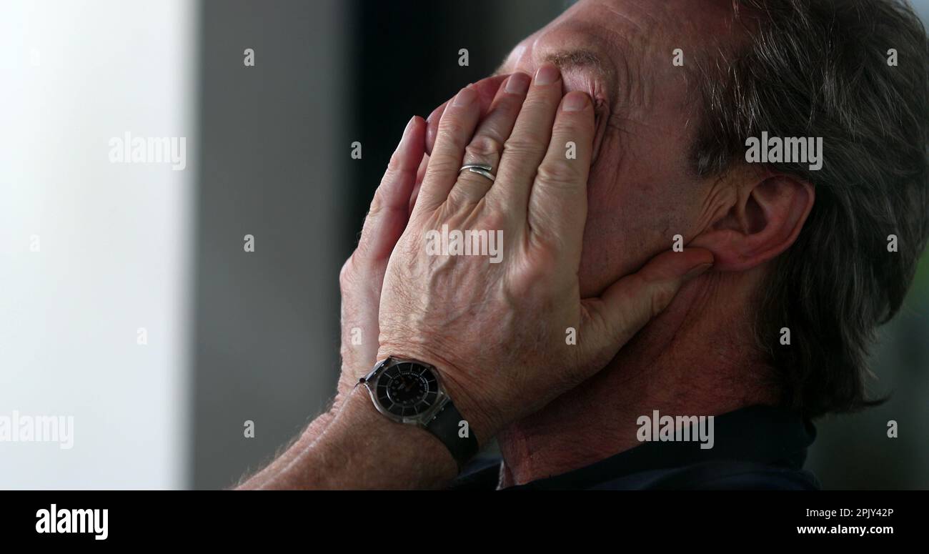 Older man rubbing face with hand Stock Photo - Alamy