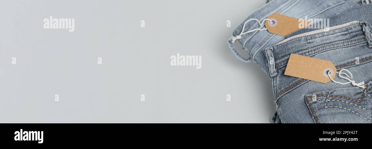 Long banner with Stack of gray jeans and empty tags Stock Photo - Alamy