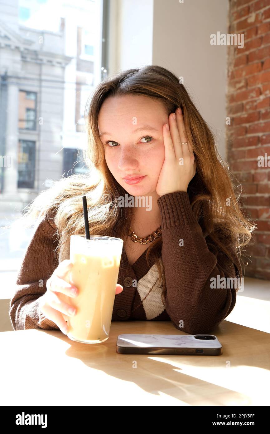 teenage girl with a cup of cold latte coffee in restaurant cafe against ...