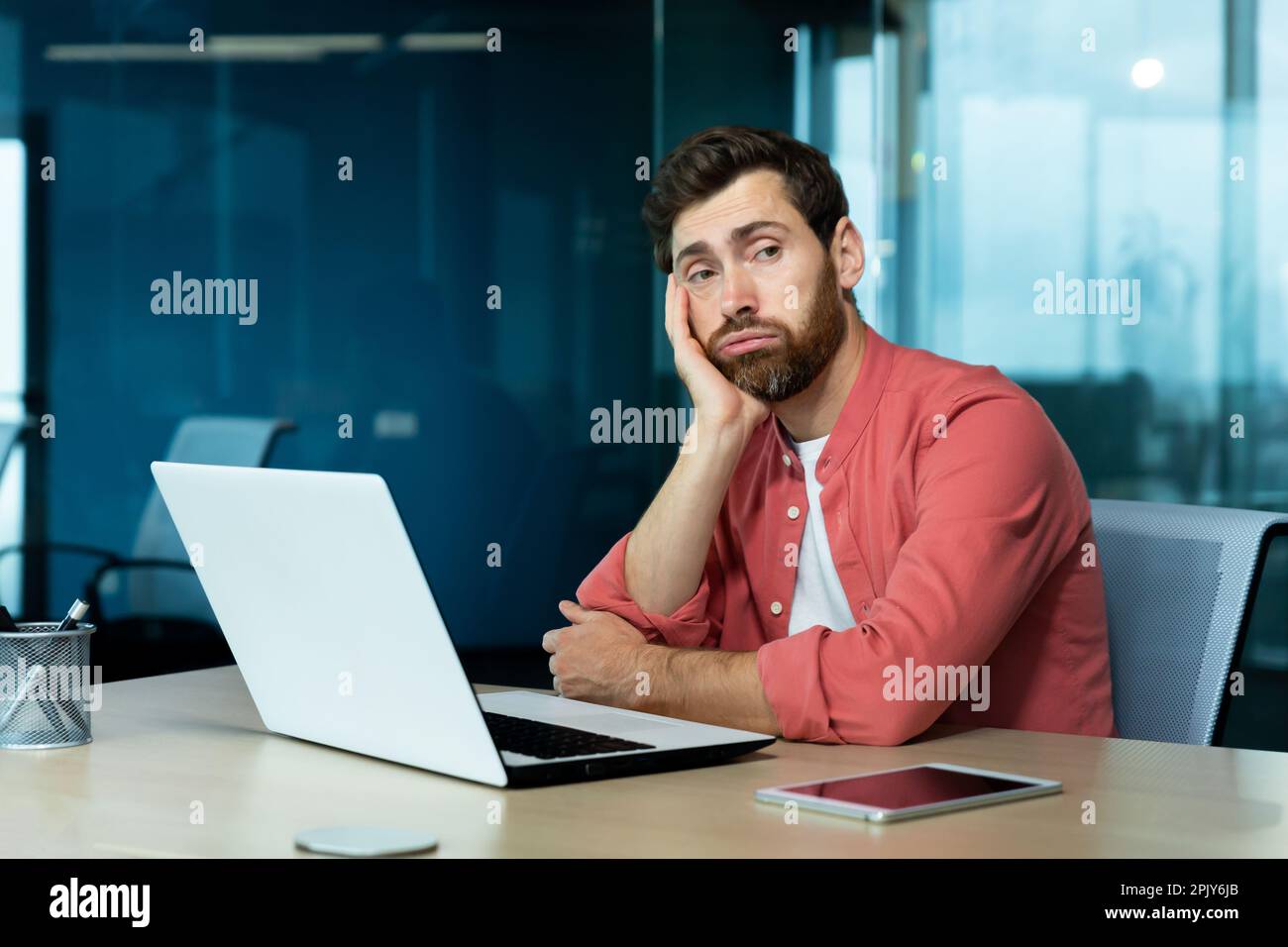 Boring office work. A young man sits in the office at a table with a ...