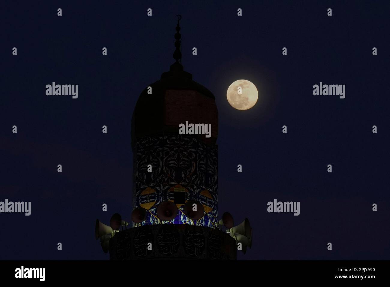The moon appears above The 14th of Ramadan Mosque in central Baghdad ...