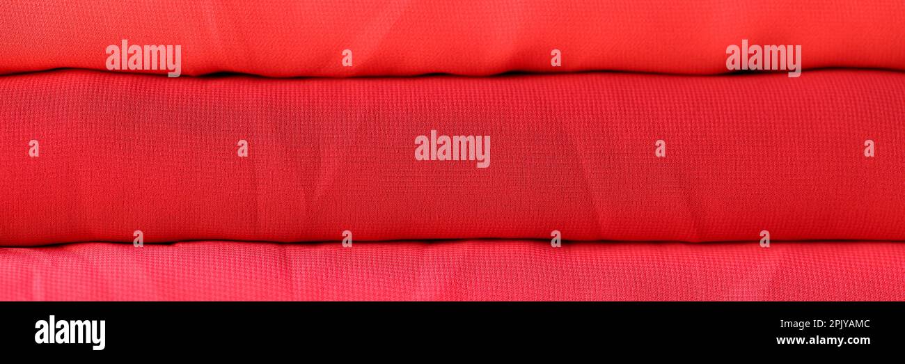 Red rolls of knitted fabric texture background Stock Photo - Alamy