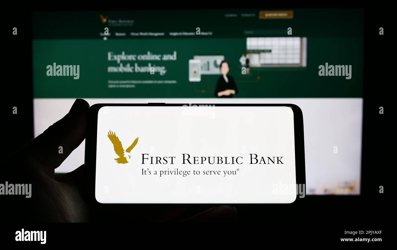 Person holding smartphone with logo of commercial banking company First ...