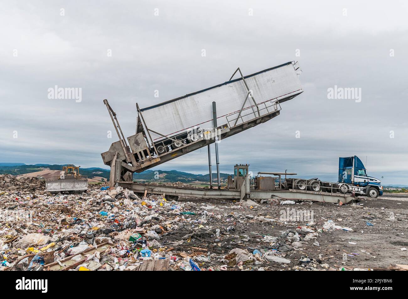 Landfill tipper lifts trailer container to dump all the trash into an ...