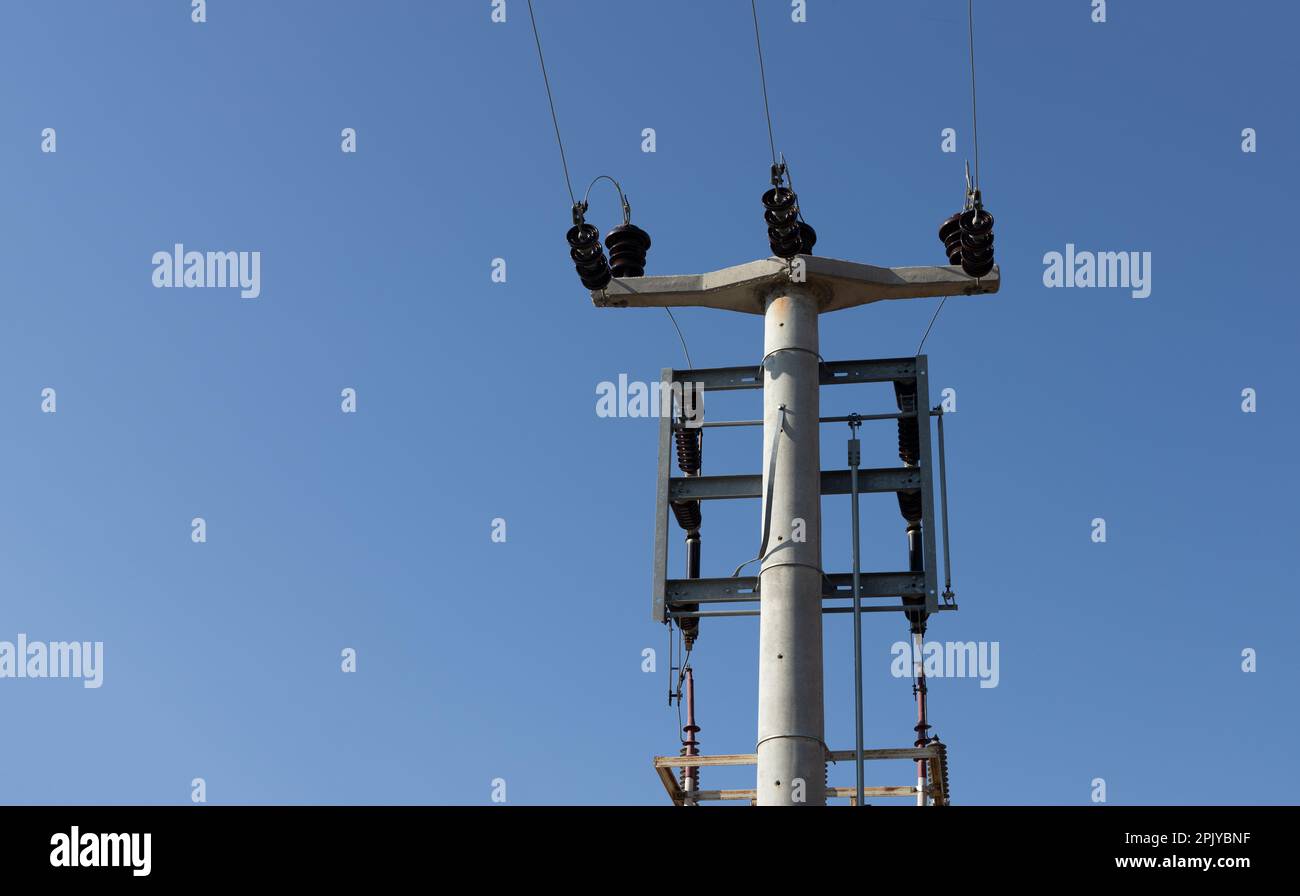 High-voltage pole with insulators and wires against blue sky. Electric ...