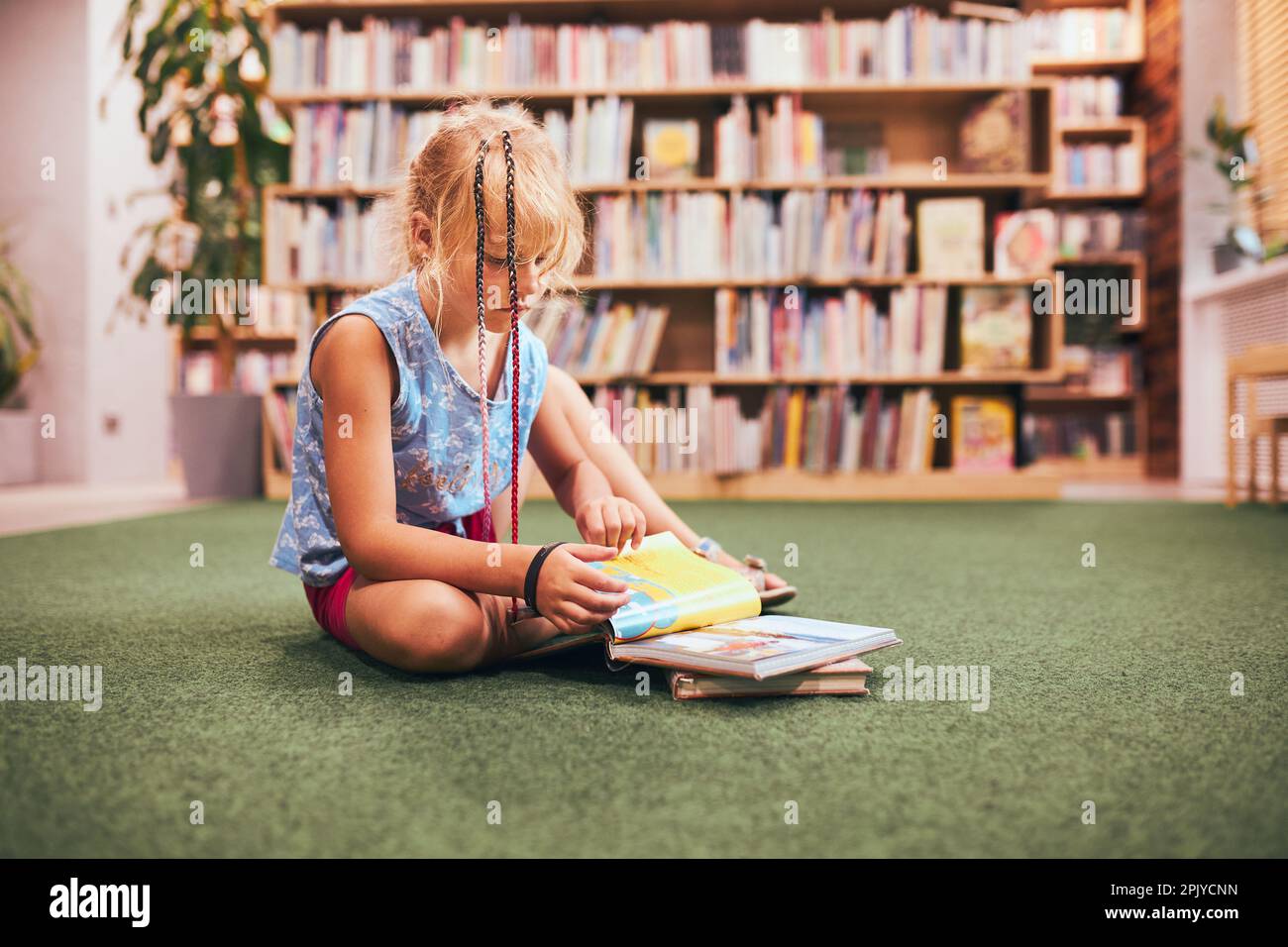 Schoolgirl reading and watching book in school library. Doing homework ...