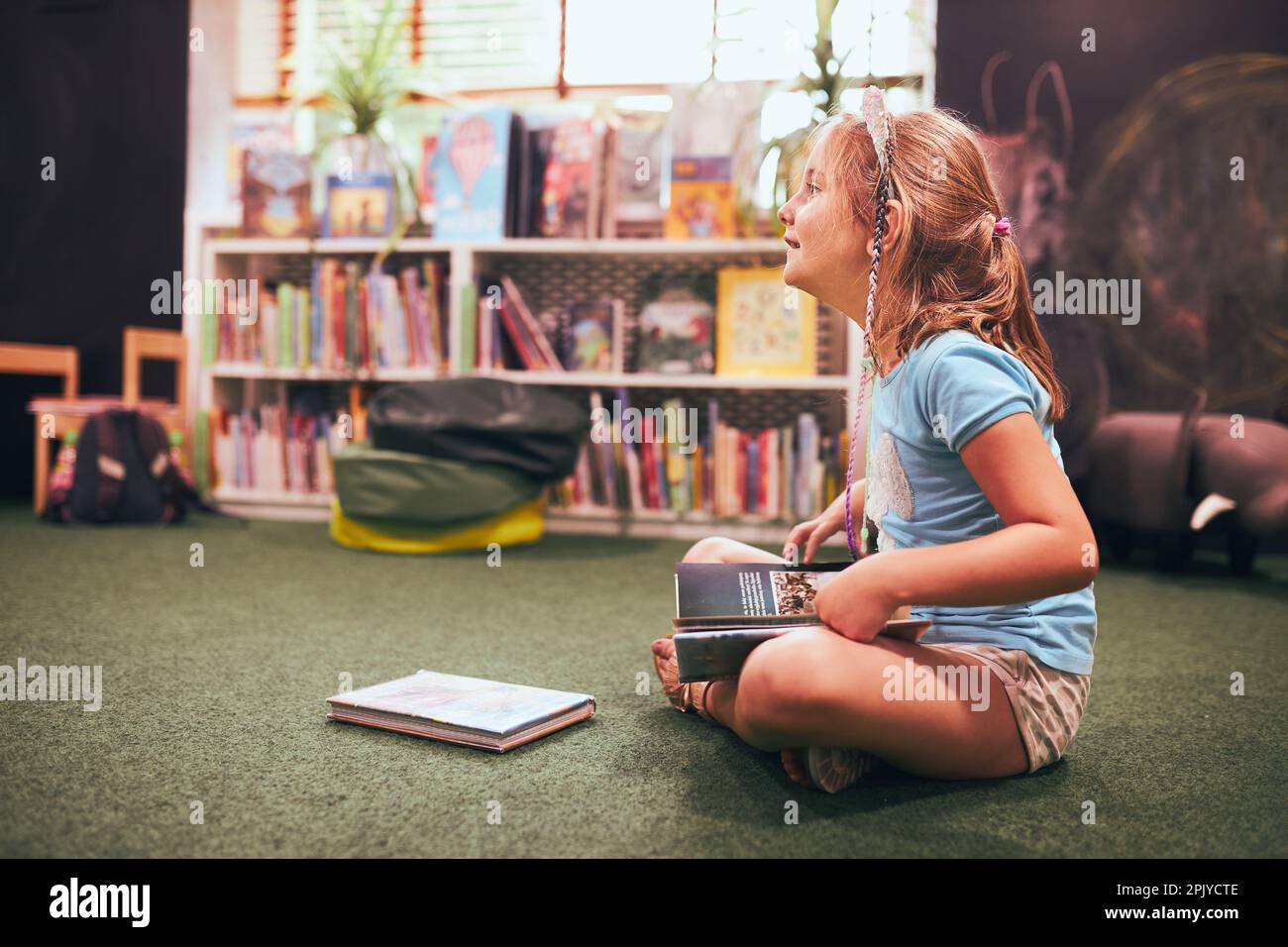 Primary schoolgirl doing homework in school library. Student learning ...