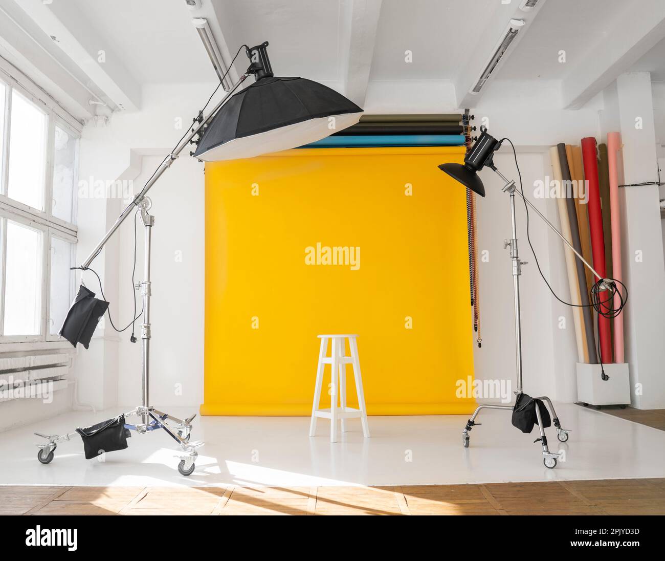 Yellow background roll with a white chair and two professional flash on ...