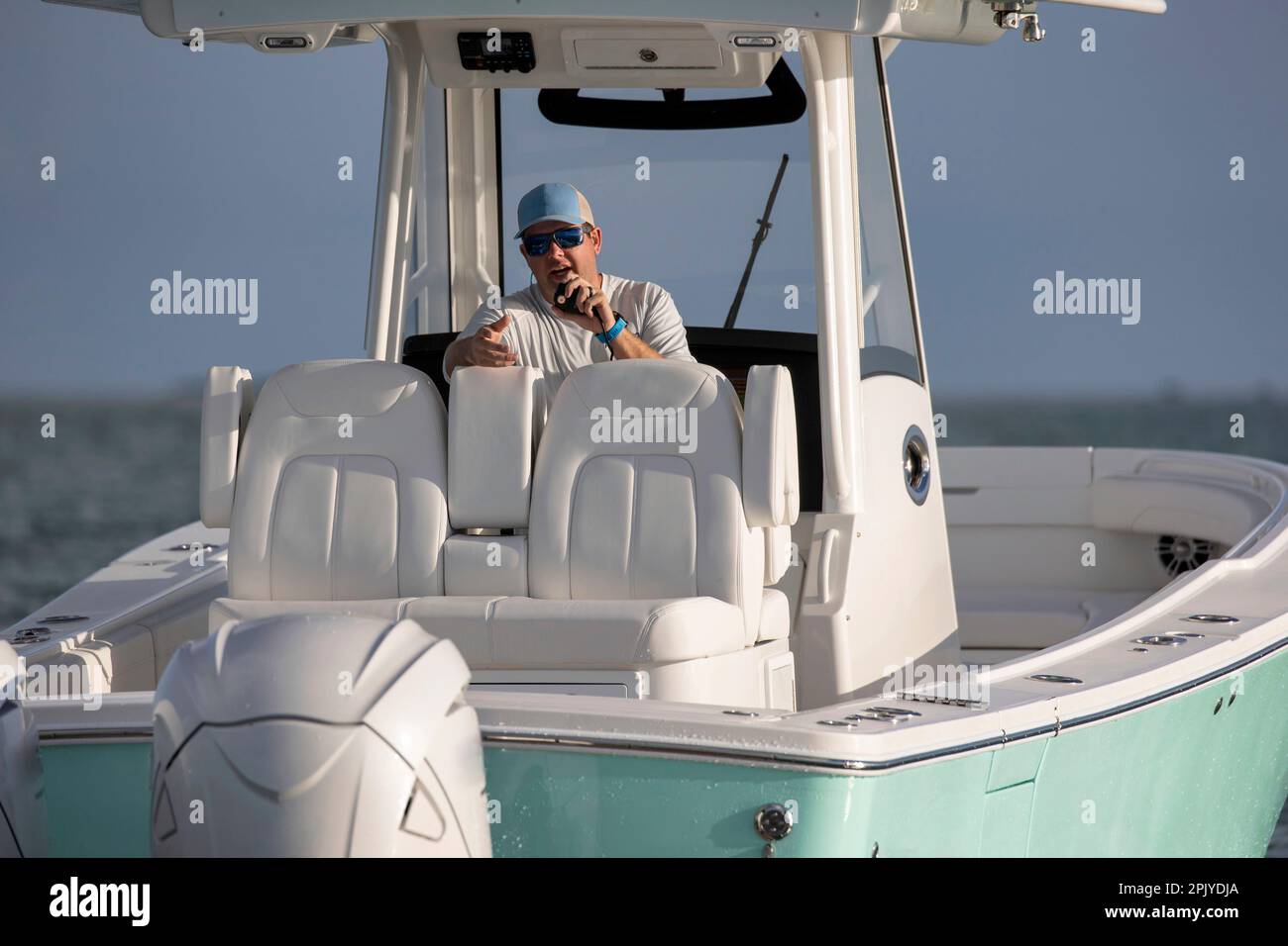 A man talking into a radio microphone on a center console boat Stock ...