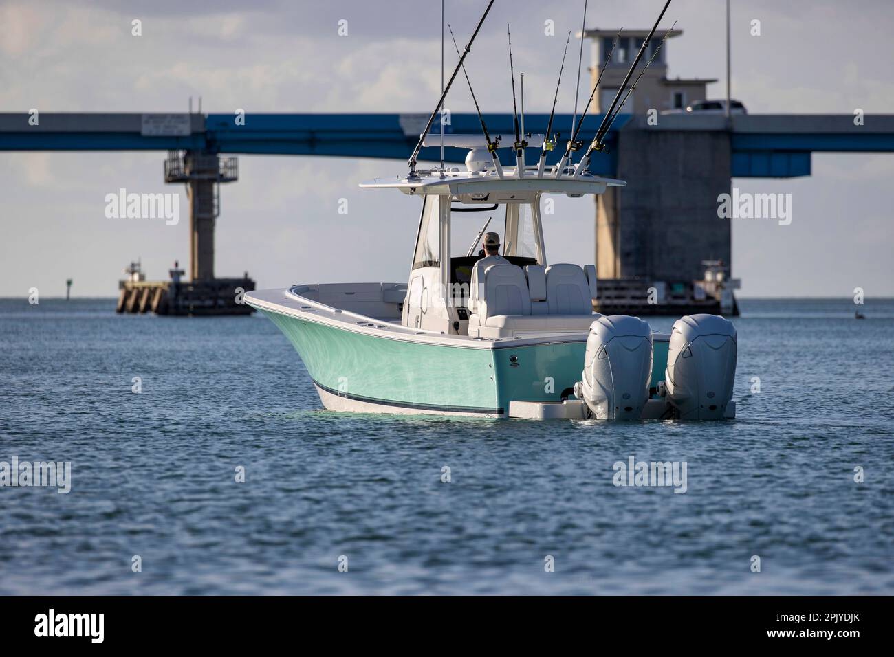 A center console fishing boat slowly approaching a bridge Stock Photo ...
