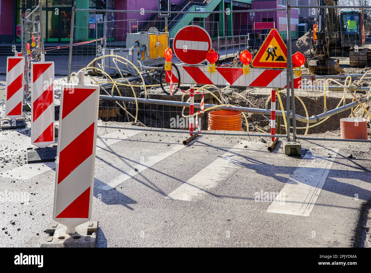 Street repair site with red and white striped vertical warning bollards ...