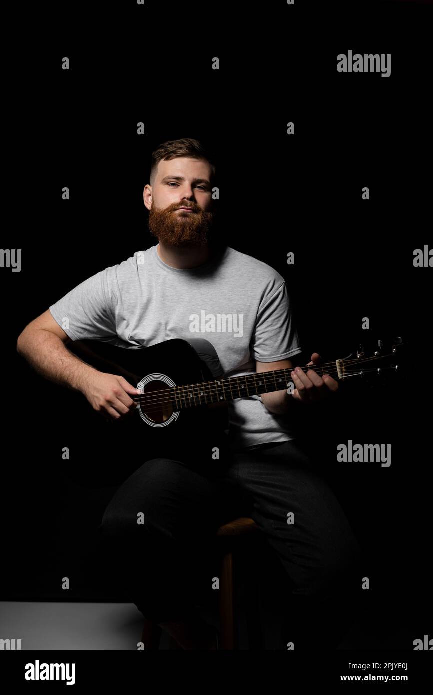 Handsome brunette bearded man musician plays an acoustic guitar in a ...