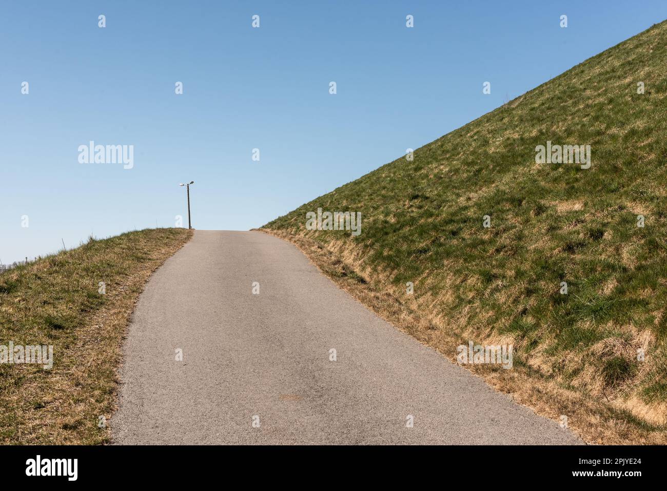 Steep uphill road with grass fields on each side Stock Photo - Alamy