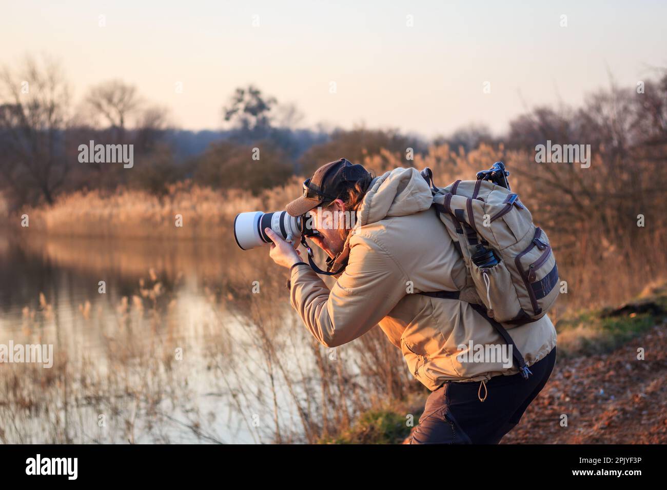 Photographer with camera, telephoto lens and backpack taking picture at ...