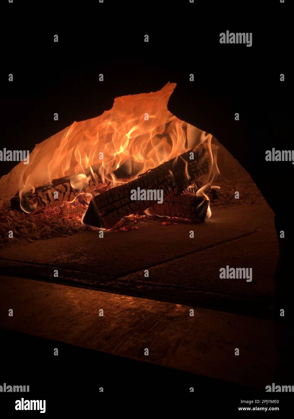 The wood is flaming in the oven with an open flame burning brightly in ...