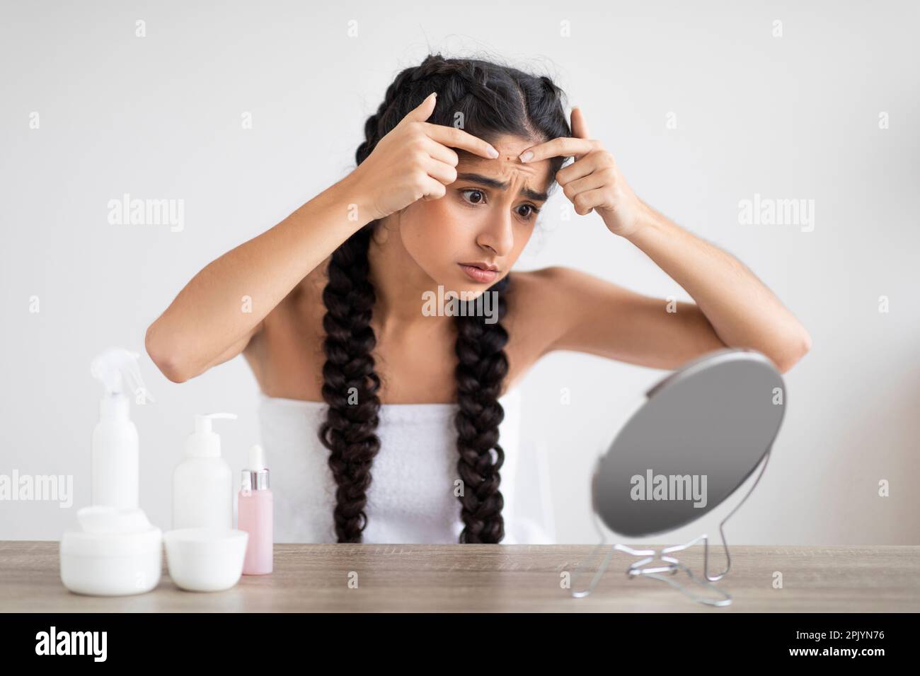 Upset Young Indian Female Popping Pimple On Forehead While Looking In ...