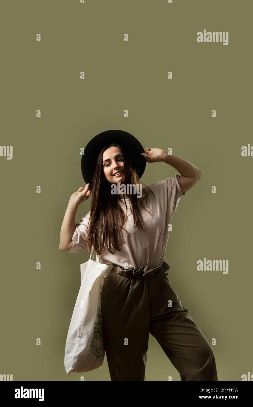 Cherfull brunette woman in beige t-shirt and black hat holding a mesh ...