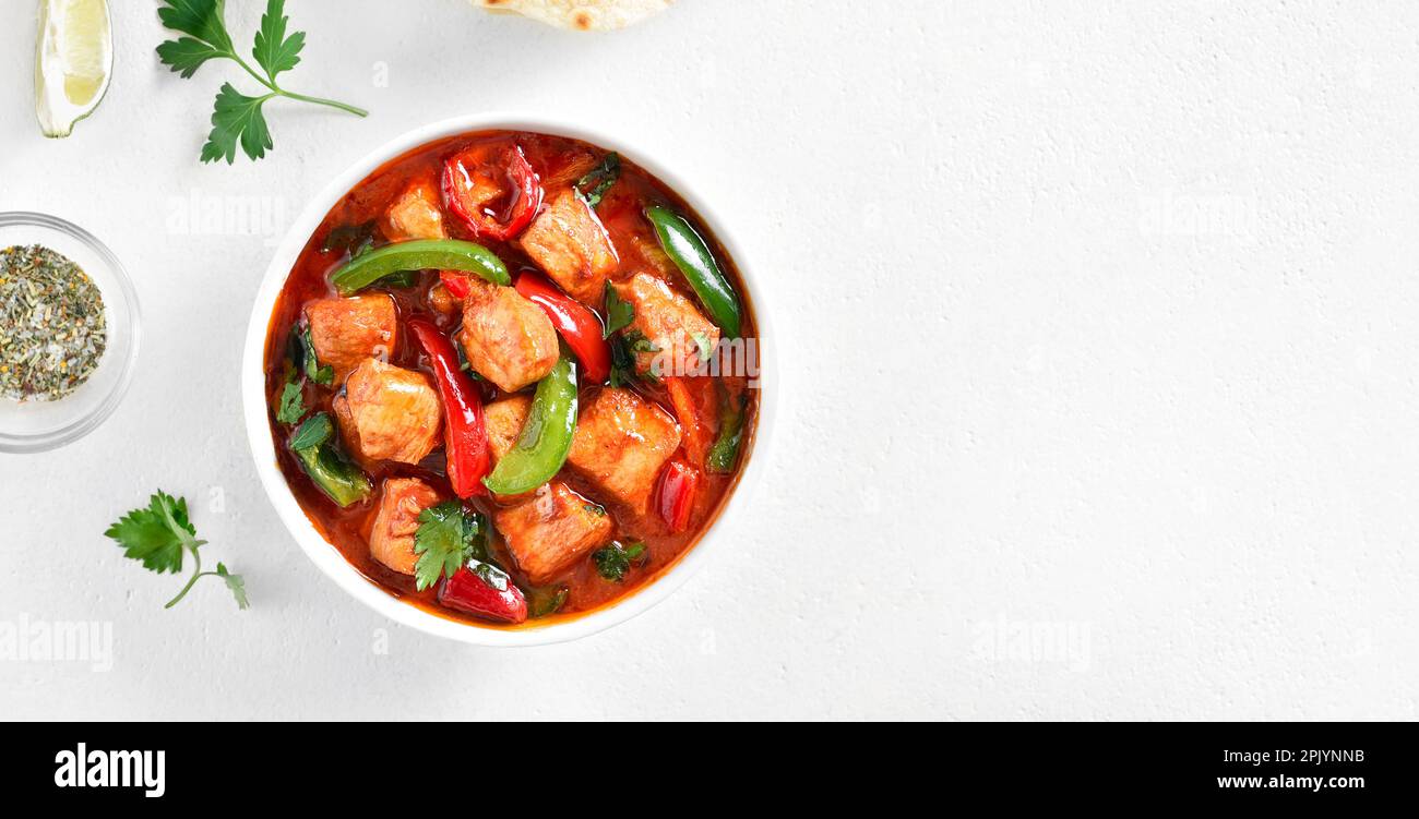 Thai style red chicken curry with vegetables in bowl over light ...