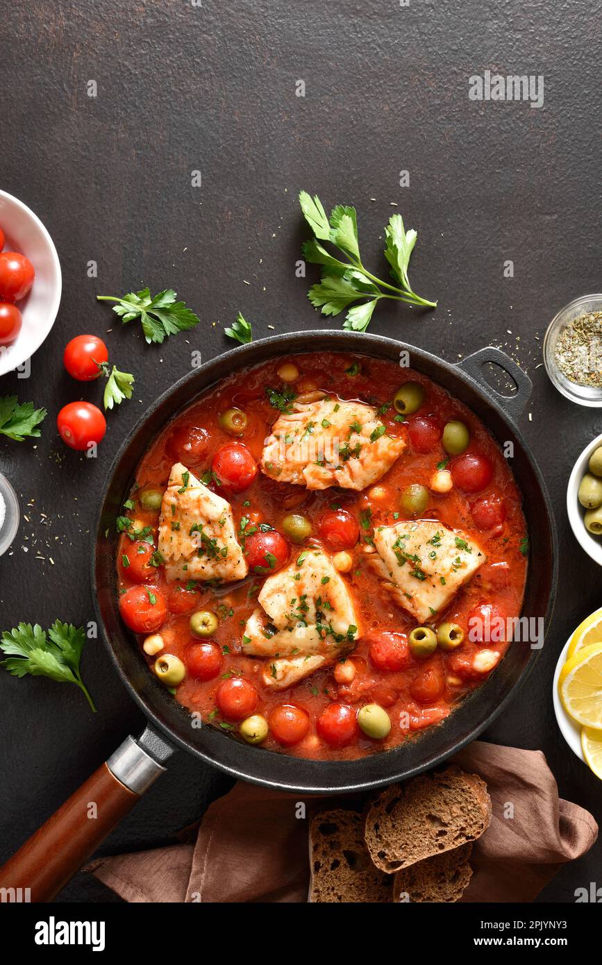 Cod stew with chickpeas, cherry tomatoes and olives in cast iron pan ...