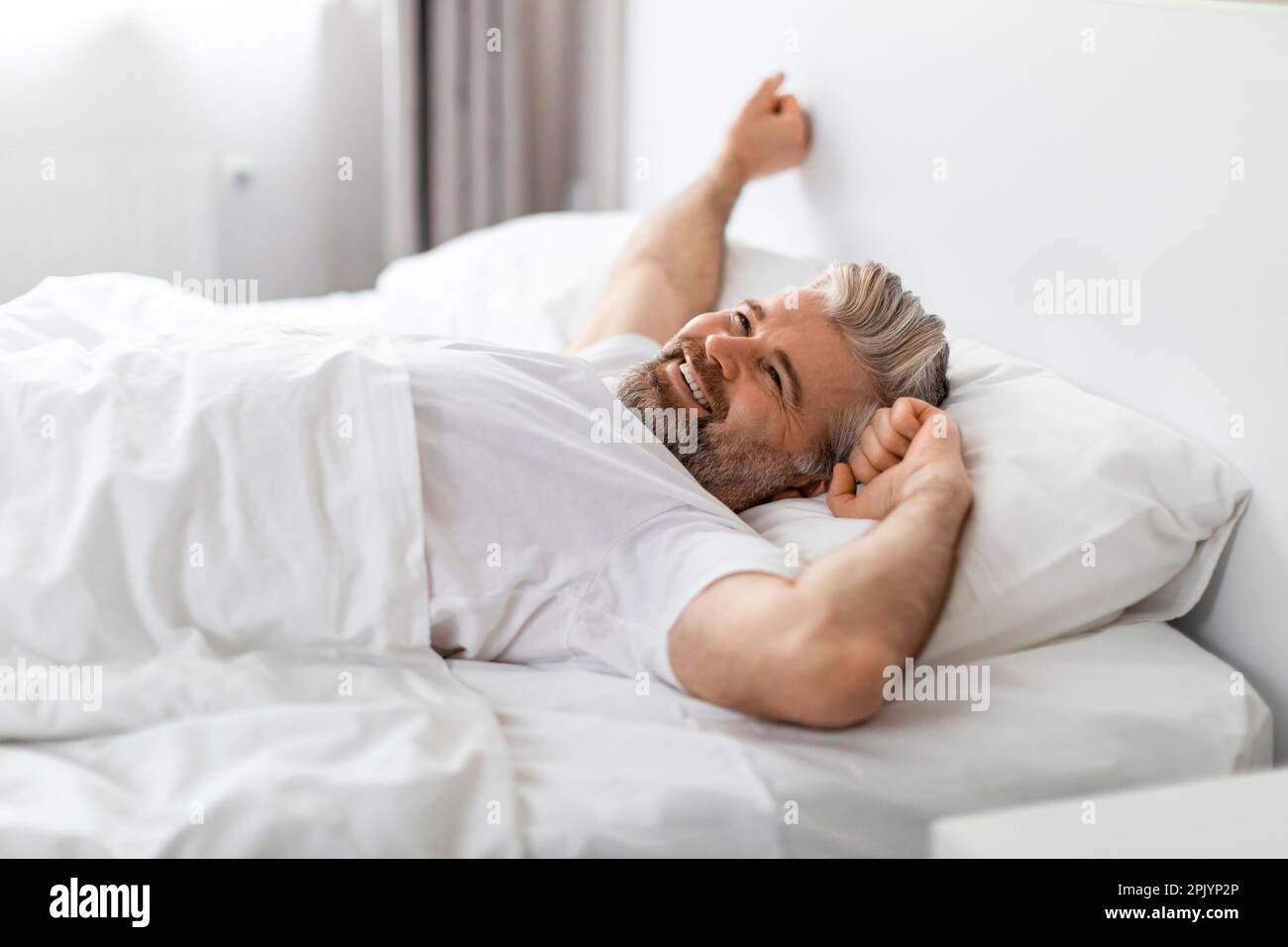 Positive mature man stretching in bed in the morning Stock Photo - Alamy