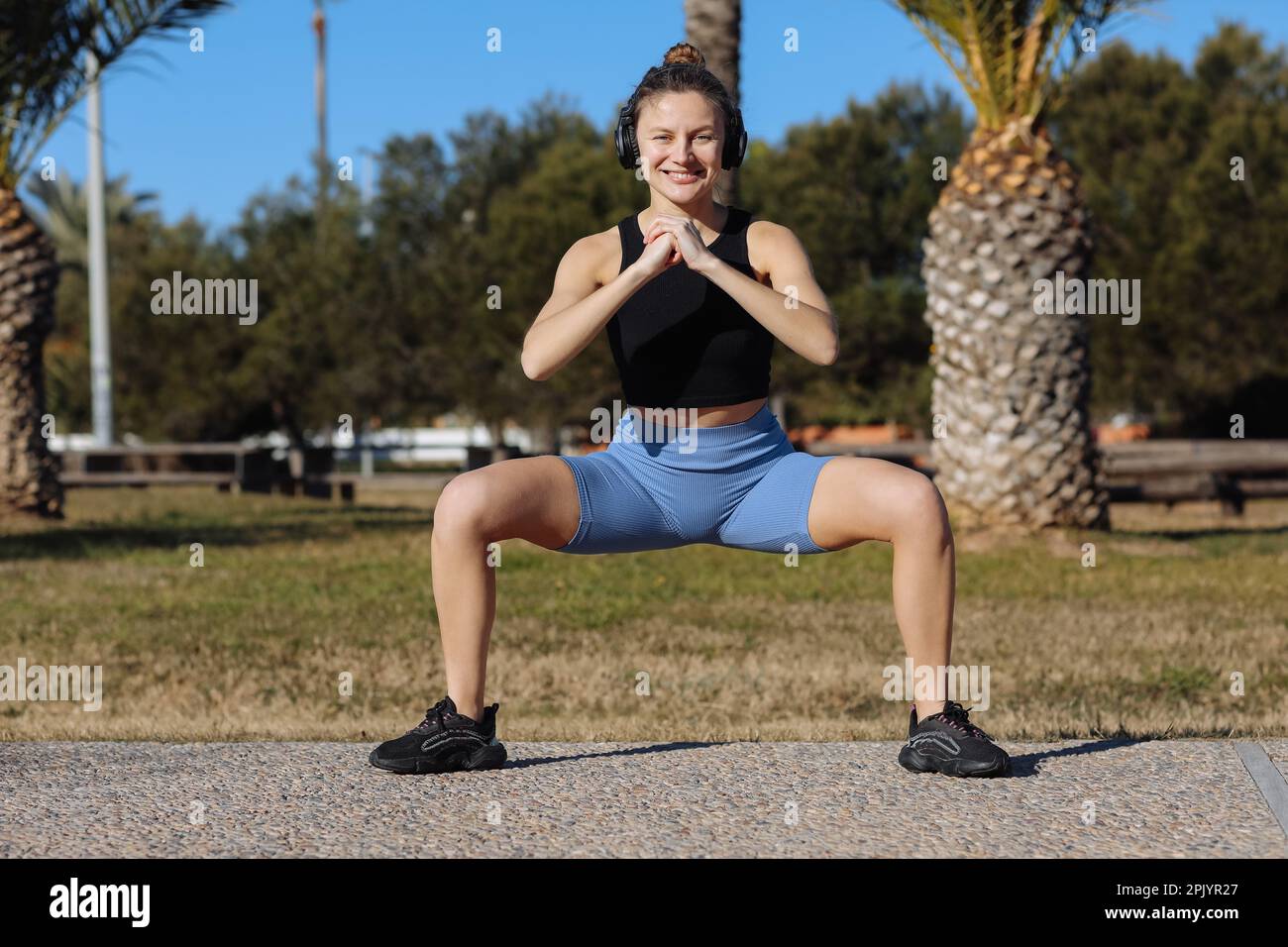 Young healthy woman in sportswear listens music in headphones while ...