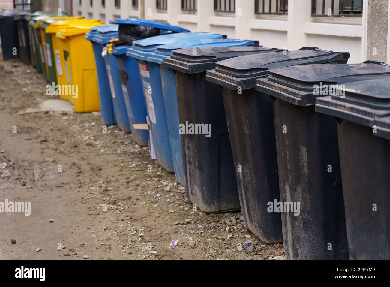 Rows of garbage cans of different colors in an alley in the city center ...