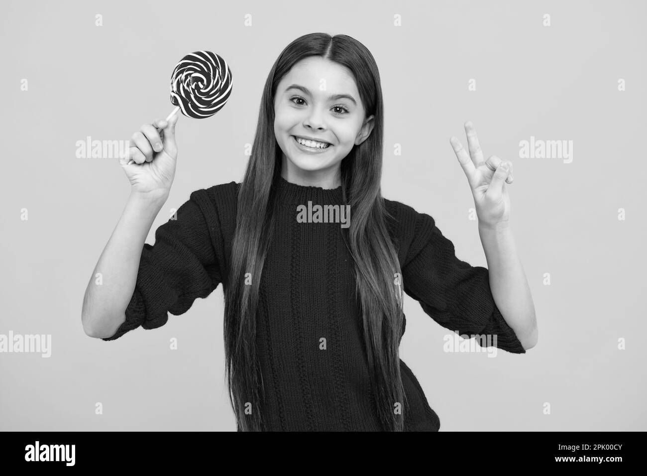 Cool teen child with lollipop over yellow isolated background. Sweet ...