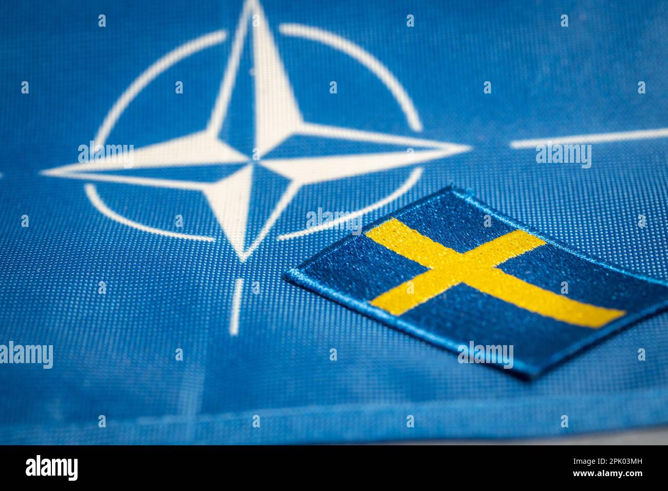 The flag of Sweden against the background of the symbol of NATO, the ...