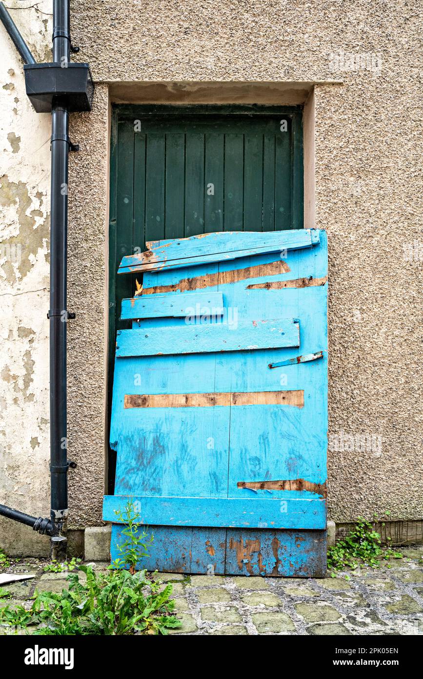 Old abandoned wooden gate leaning against commercial building back door ...