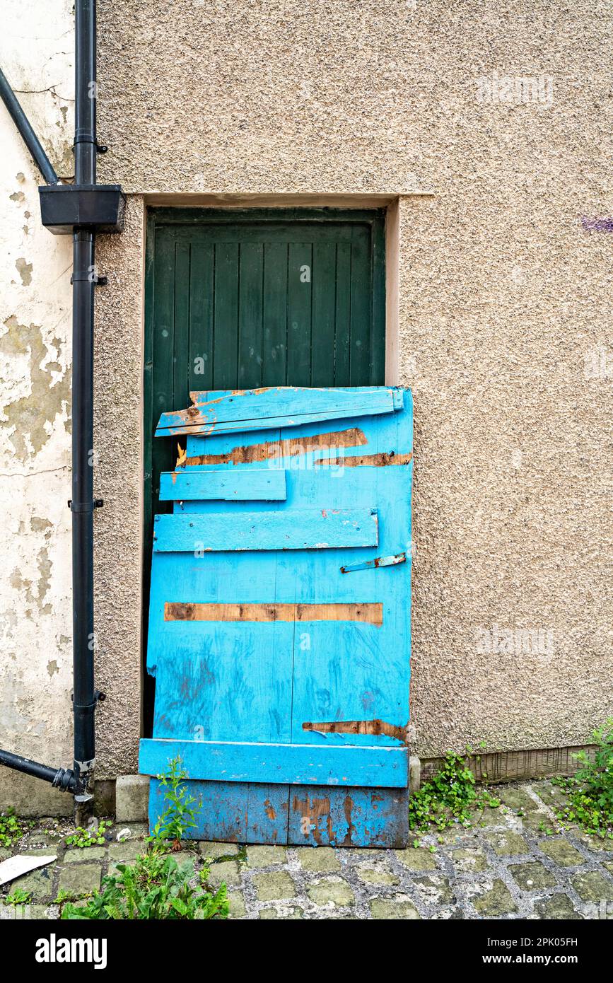 Old abandoned wooden gate leaning against commercial building back door ...