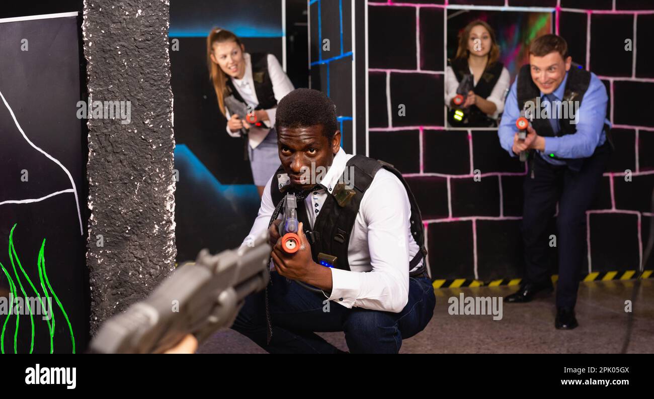 Group of colleagues holding laser pistols playing laser tag game Stock ...