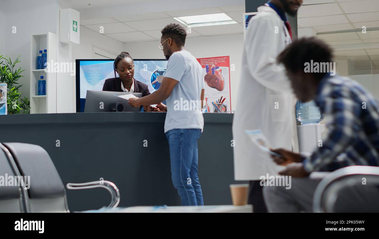 Doctor giving medical advice to person in hospital lobby, man ...
