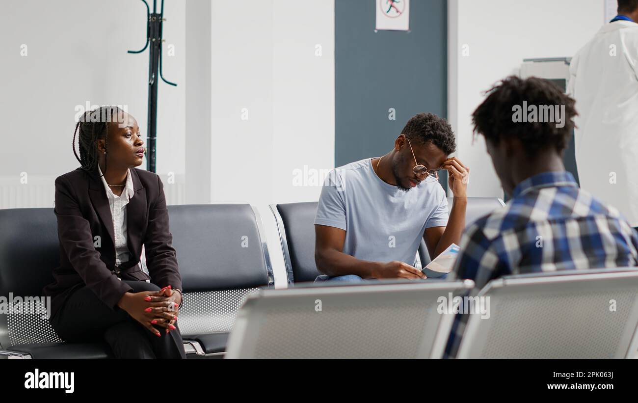 Group of patients sitting in hospital waiting room and reading medical ...